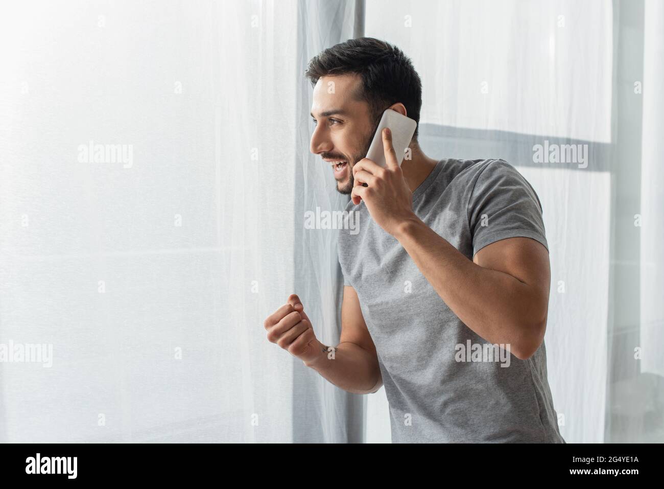Side view of excited man showing yes gesture while talking on ...