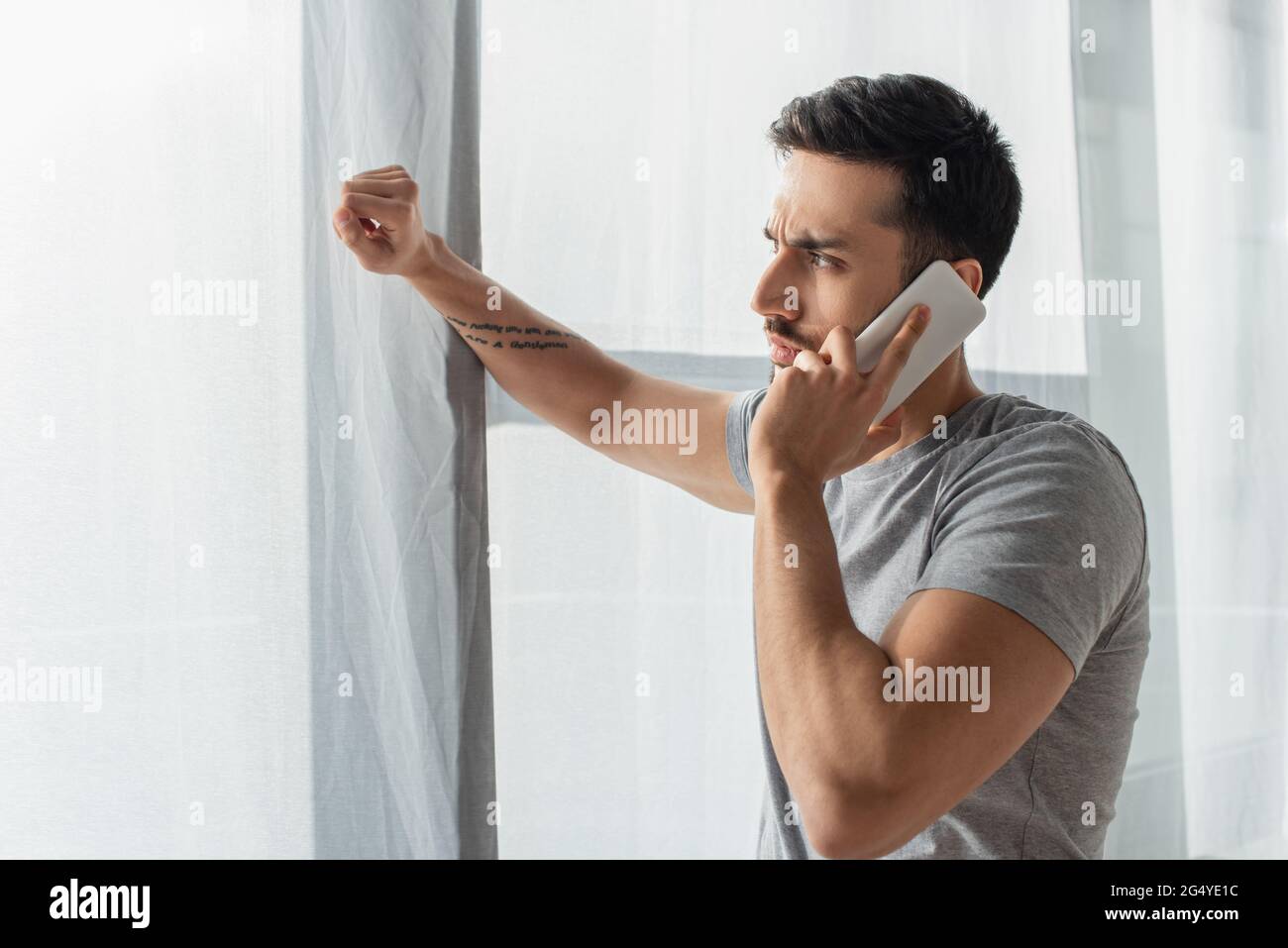 Side view of concentrated man talking on mobile phone near window Stock ...