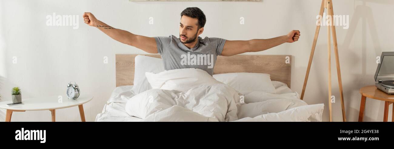 Young man stretching on bed in morning, banner Stock Photo - Alamy