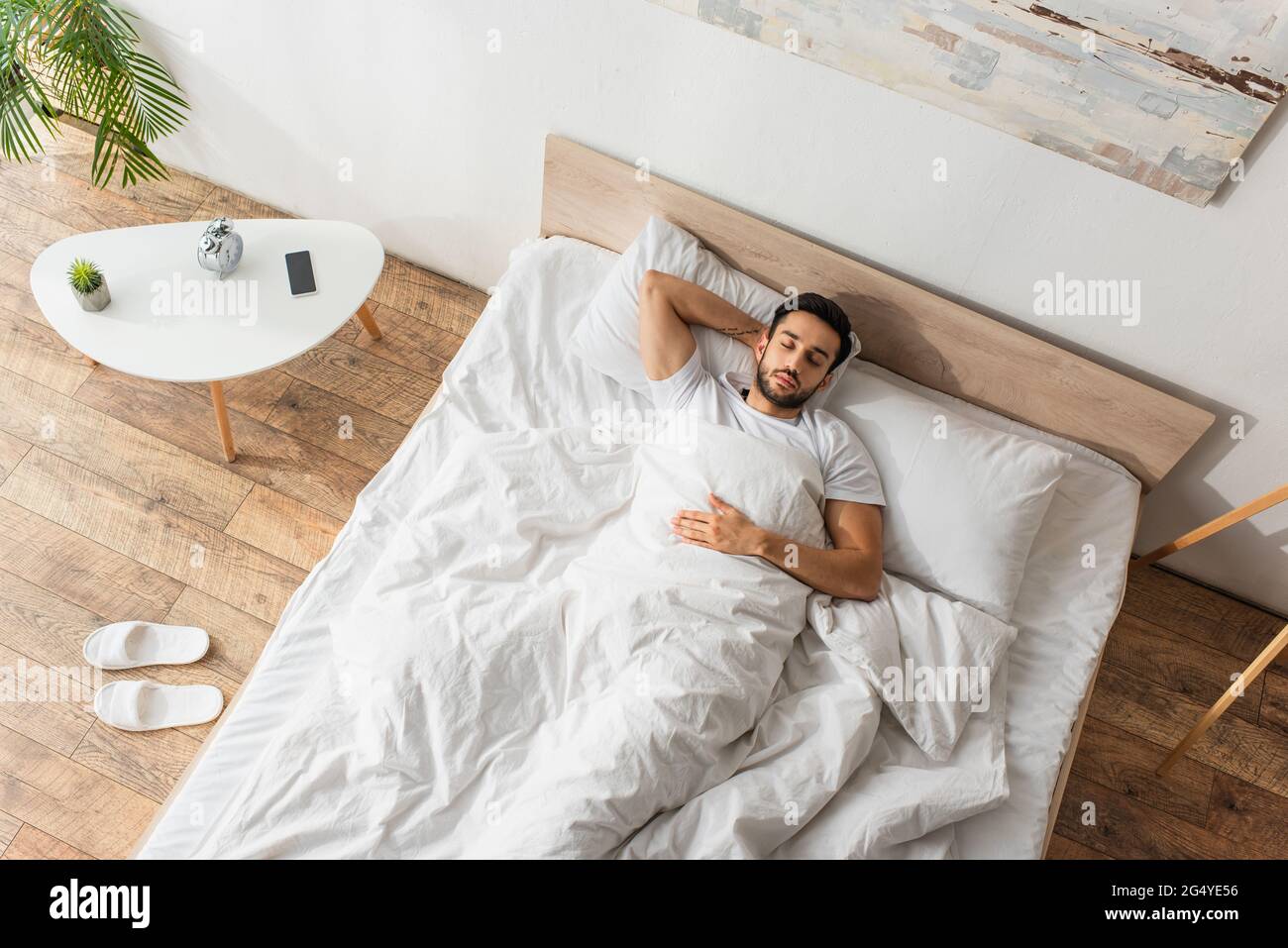 Top view of man sleeping on bed near slippers and smartphone in bedroom ...