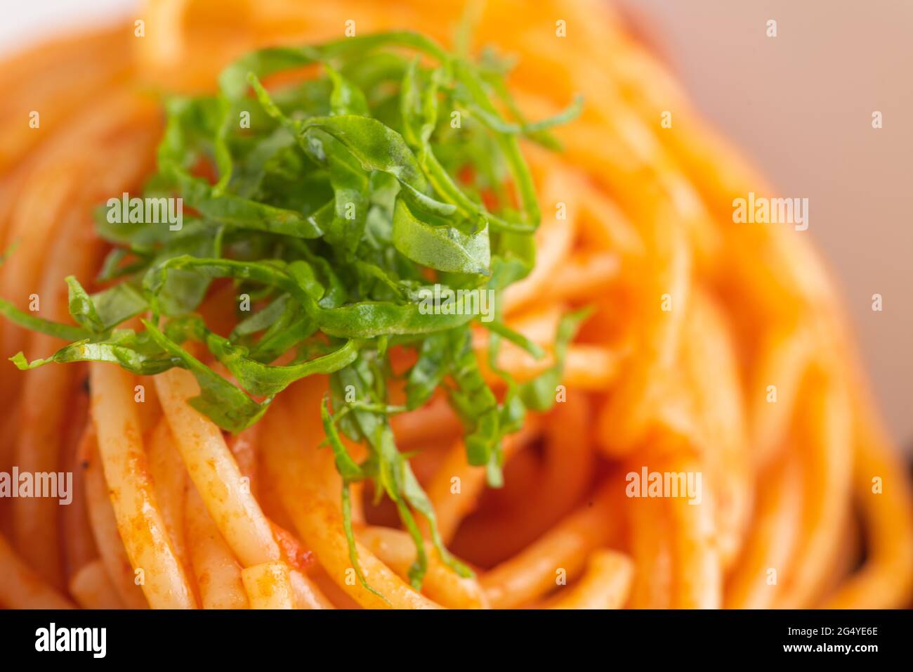 A bowl of spaghetti with burned tomatos and shredded basil Stock Photo ...