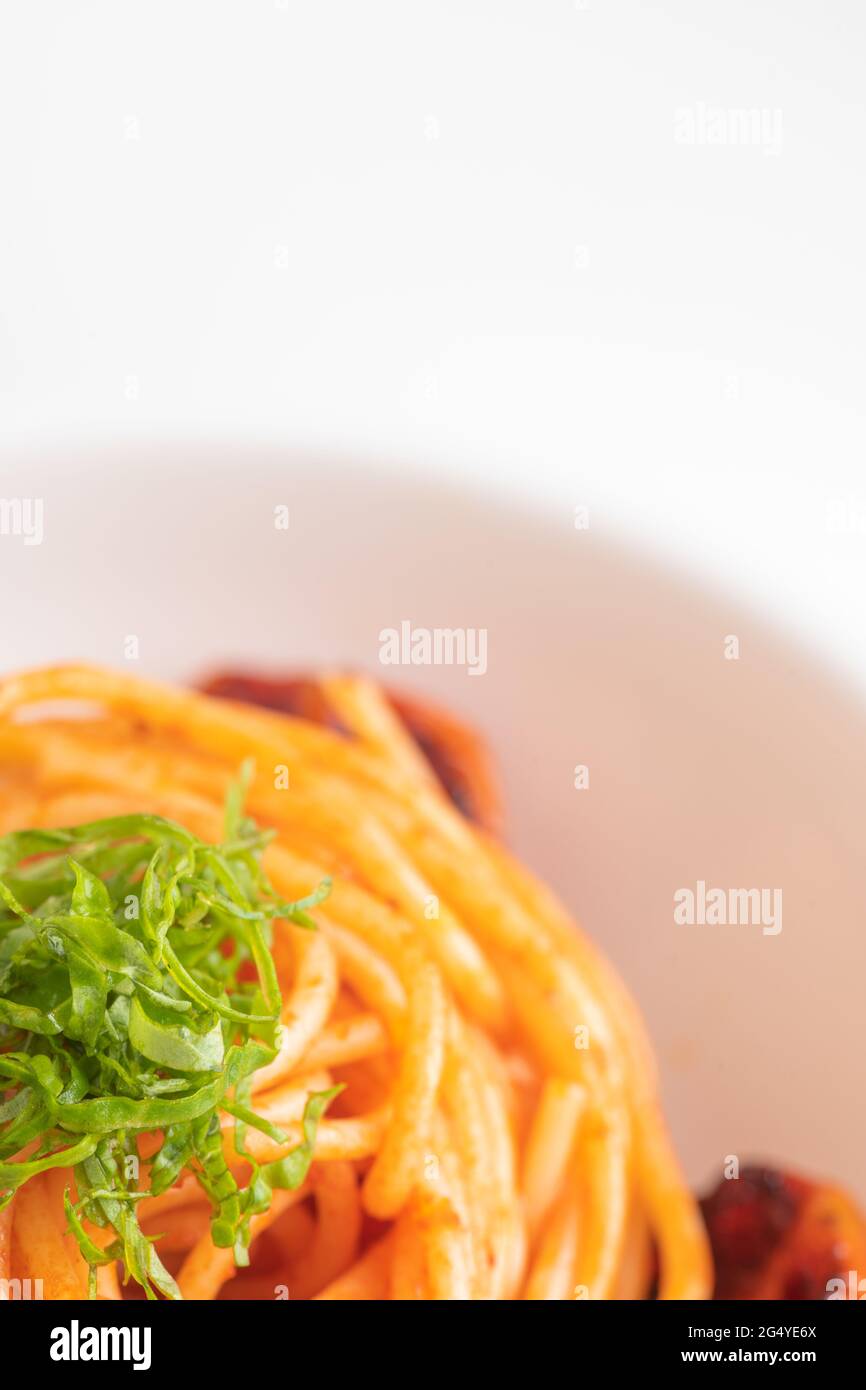 A bowl of spaghetti with burned tomatos and shredded basil Stock Photo ...