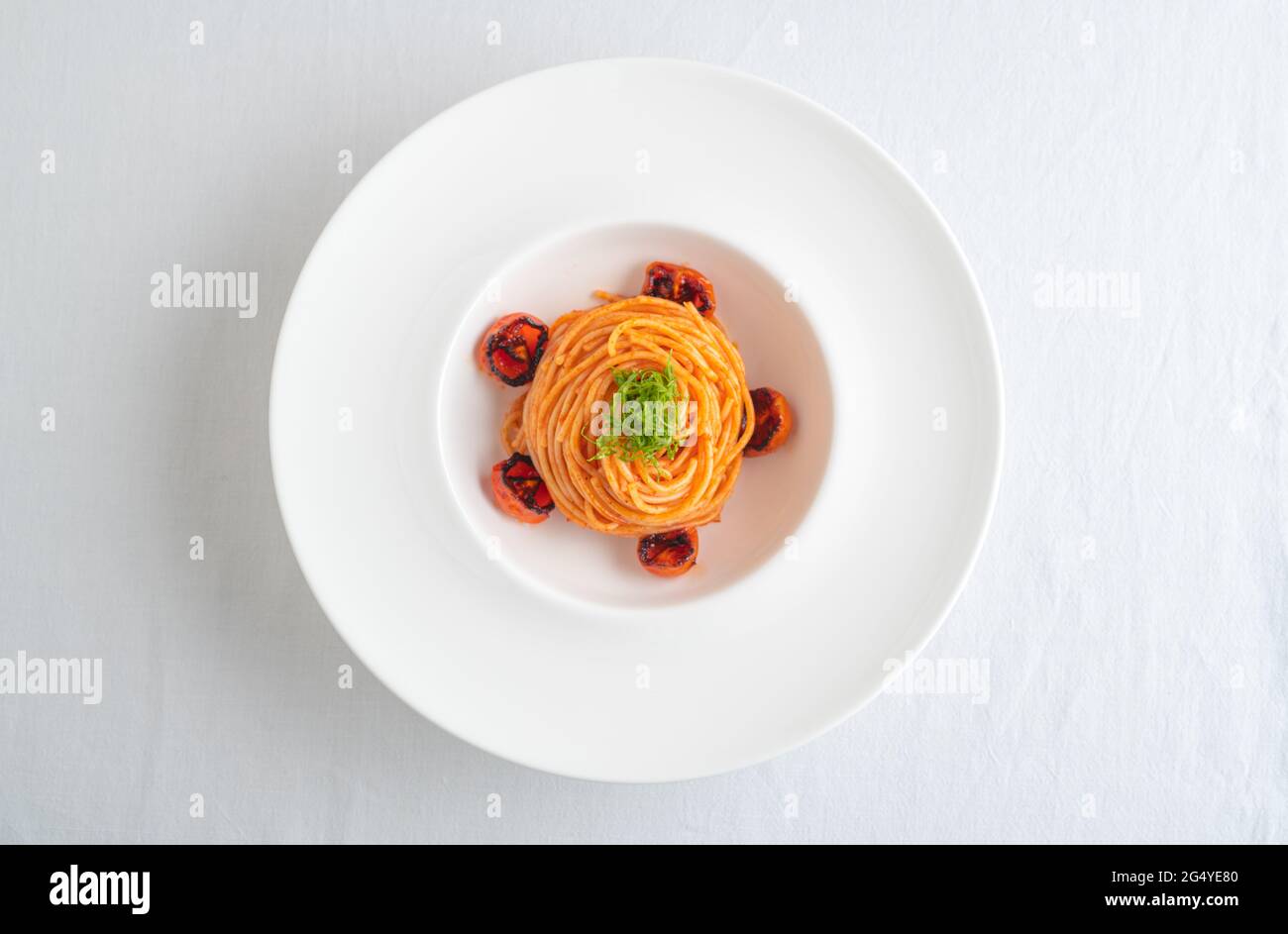 A bowl of spaghetti with burned tomatos and shredded basil Stock Photo ...