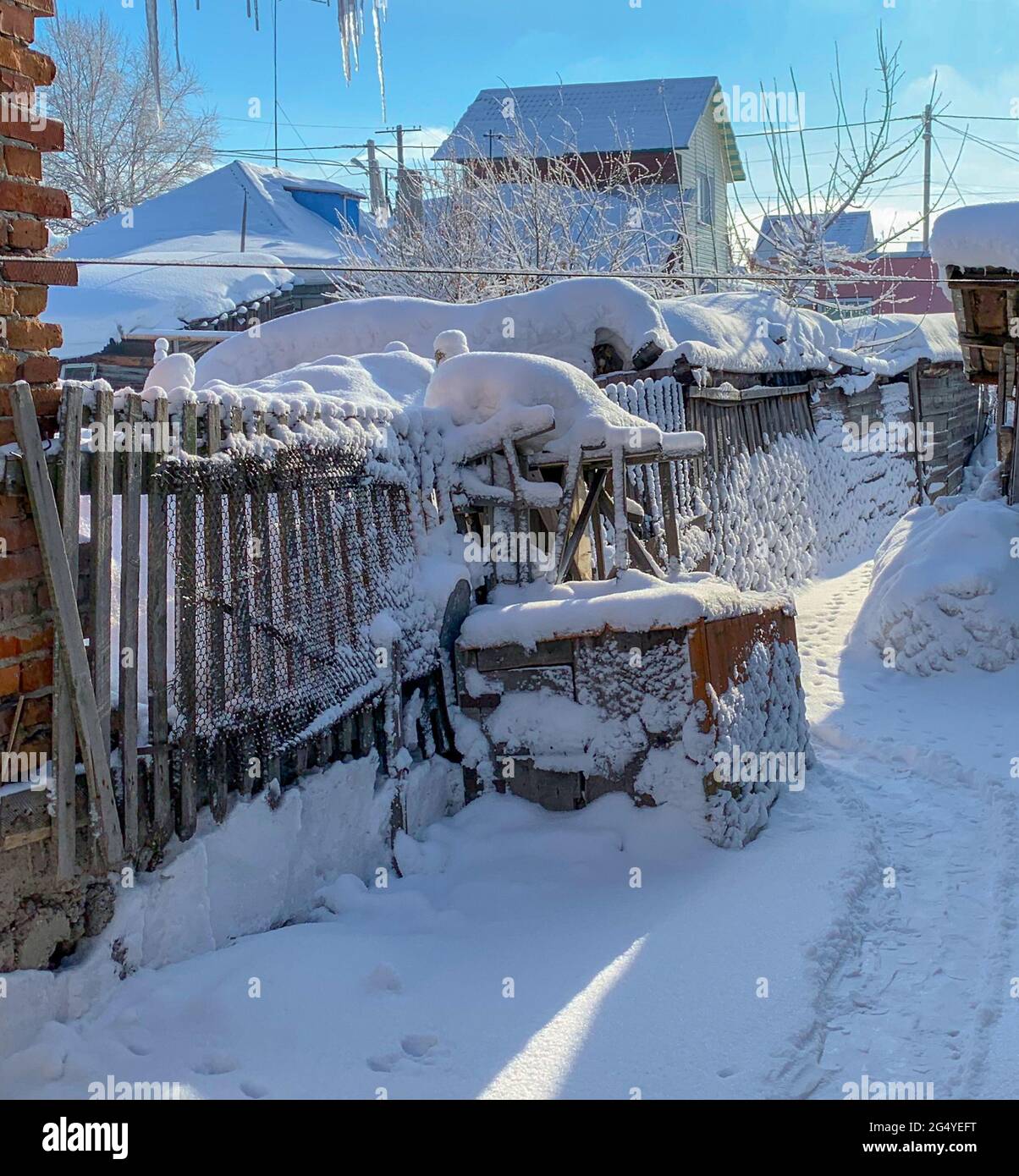 Snow-covered doghouse near a wooden fence.Country style. Hard shadows ...