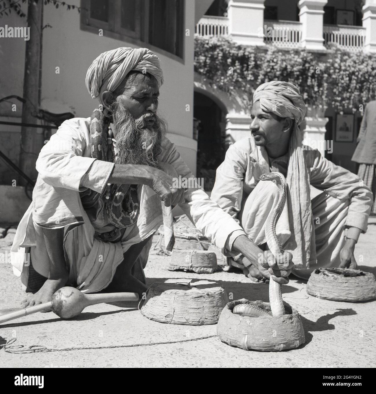 1950s, historical, two snake charmers, squatting on the floor, one ...
