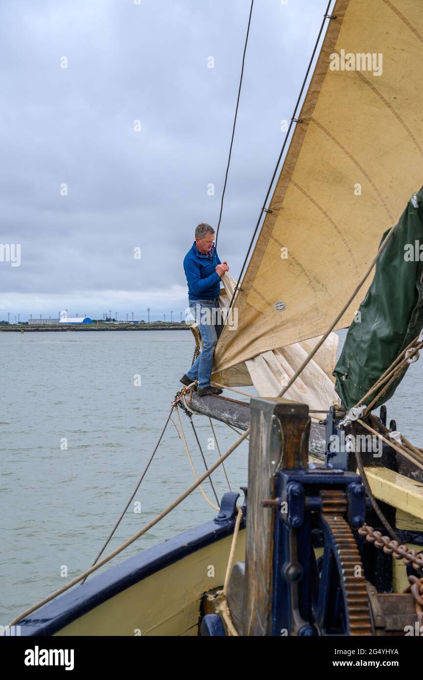Mate and volunteer Pat Fox lowering and stowing away the staysail on ...