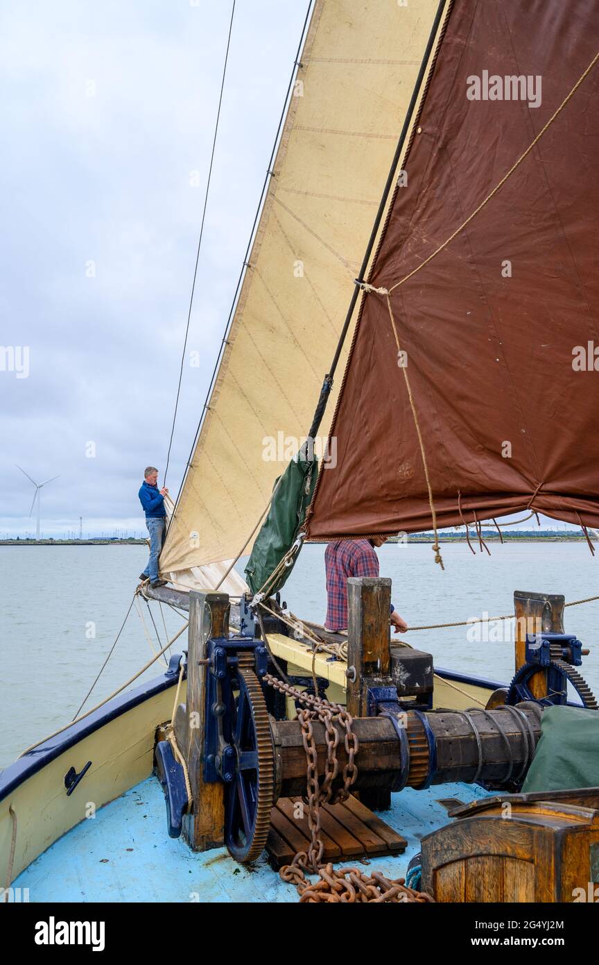 Mate and volunteer Pat Fox lowering and stowing away the staysail on ...