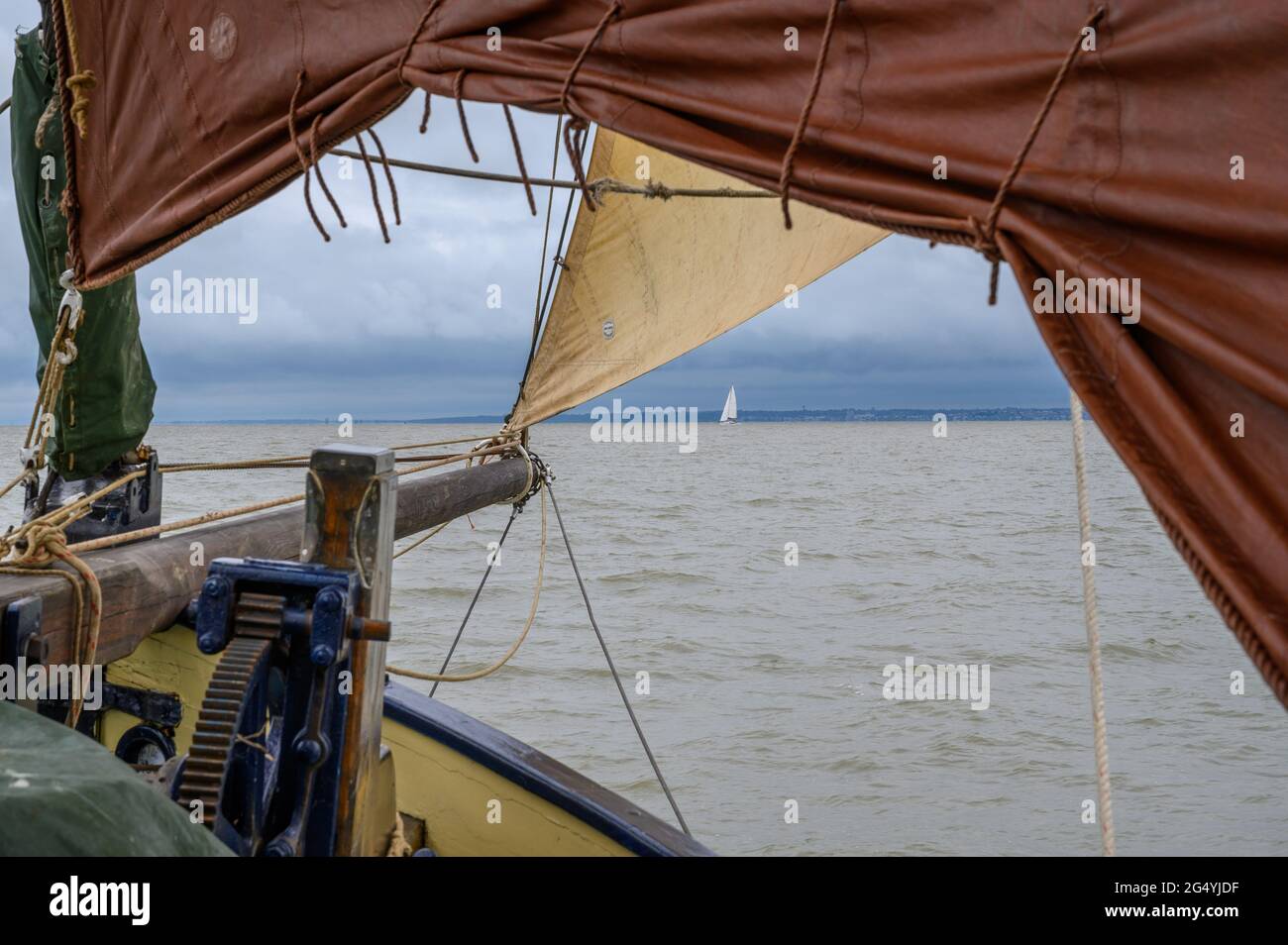 A distant sailboat seen from under the foresail and jib on the bow of ...