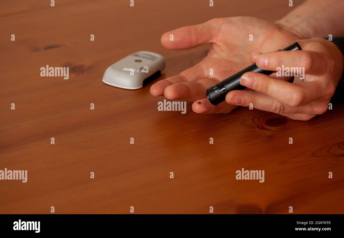 Close-up of a male hand testing blood for carbohydrates due to diabetes ...