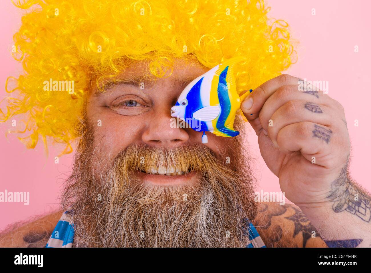 Fat happy man with beard and sunglasses have fun with a fish toy Stock ...