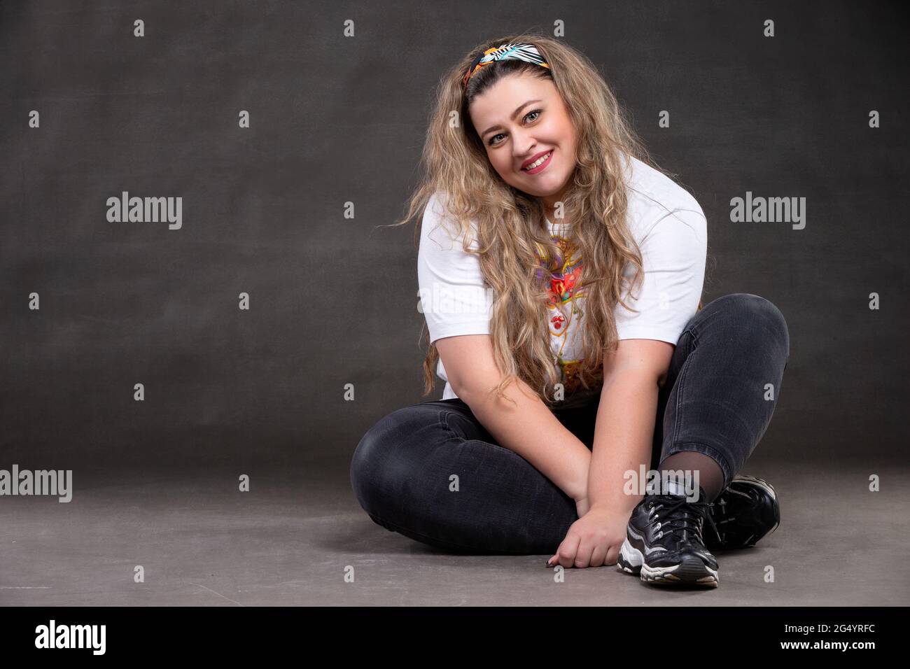 Beautiful fat woman on a gray background looks at the camera and smiles ...