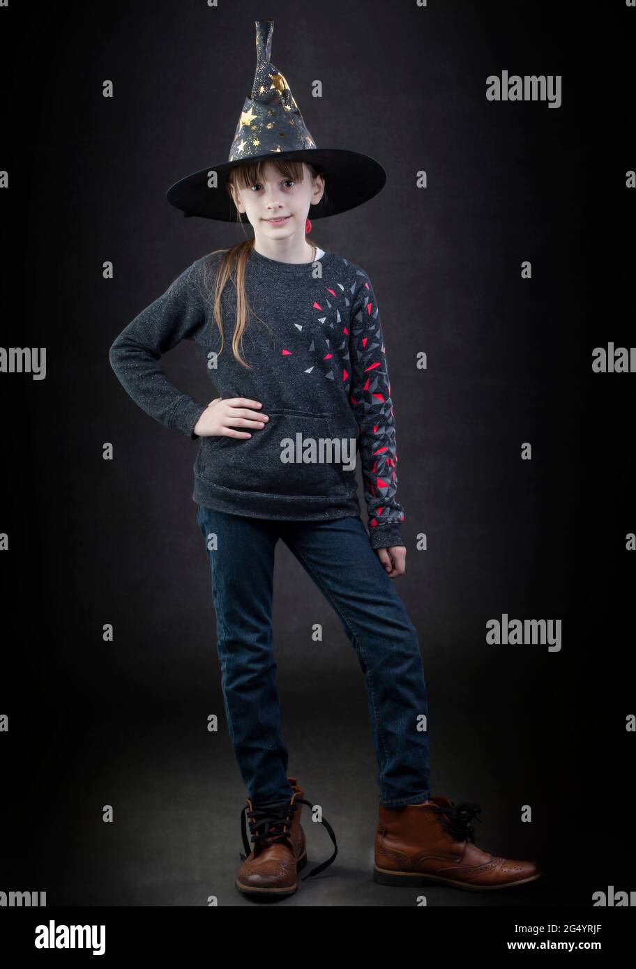 Little girl wearing a witch hat on a dark background Stock Photo - Alamy