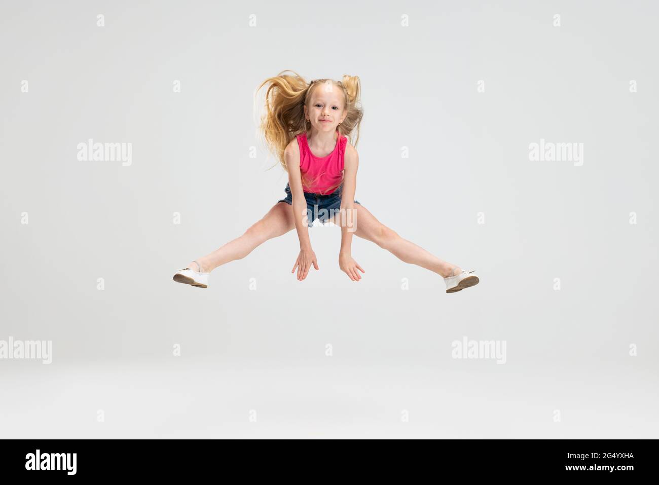 Beautiful little girl in casual clothes jumping isolated on white ...