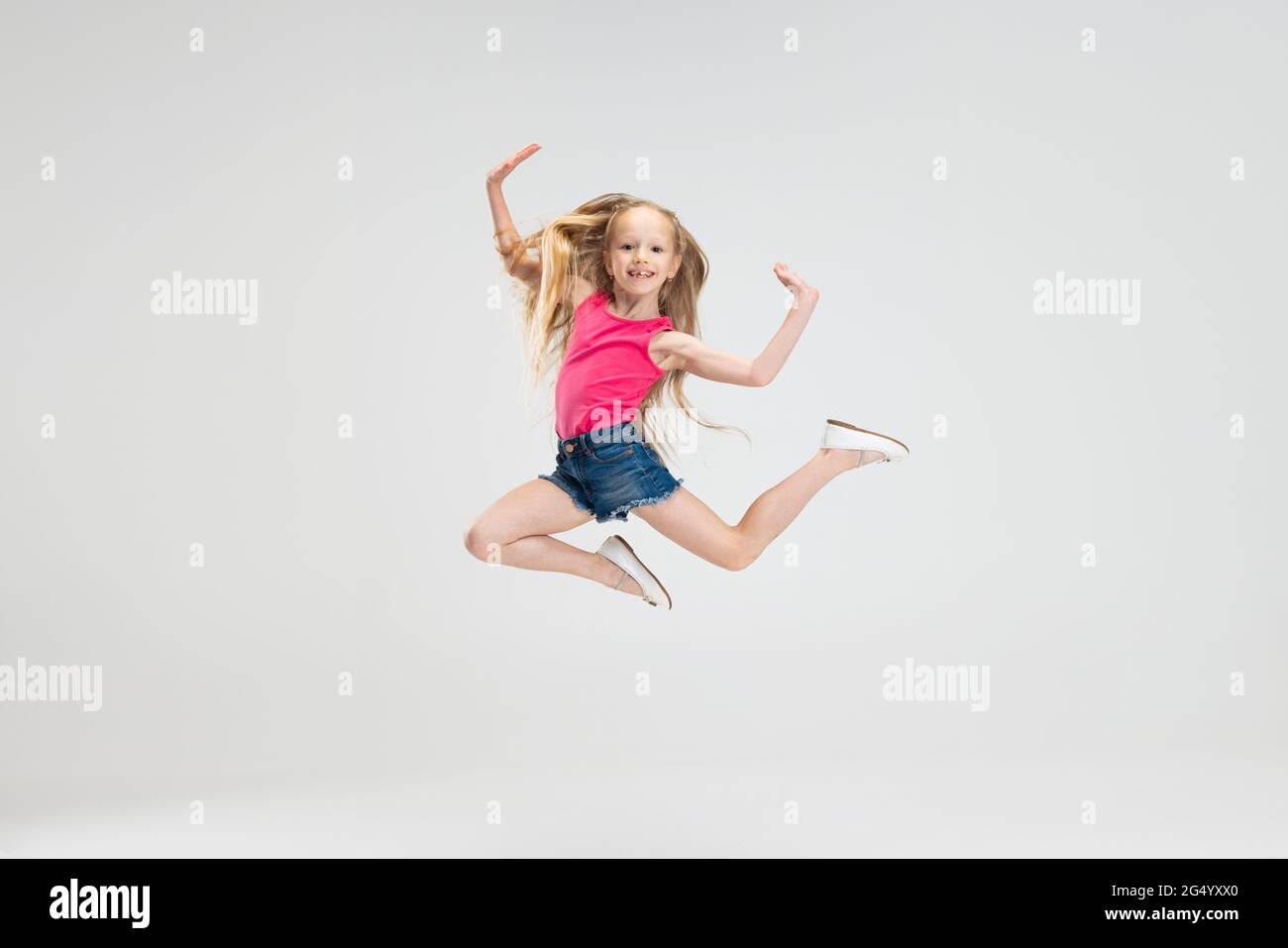 Beautiful little girl in casual clothes jumping isolated on white ...