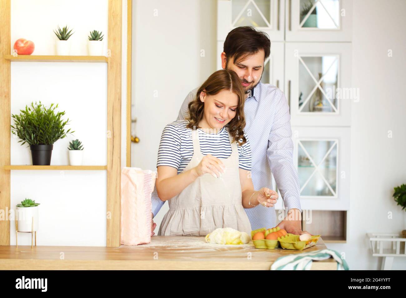 Side view of delighted couple in love hugging in kitchen while cooking ...