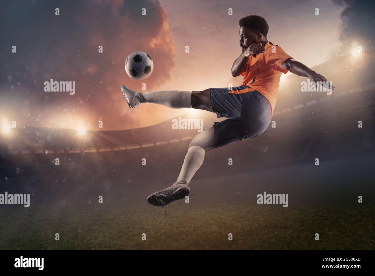 Male soccer, football player kicking ball in jump at the stadium during ...