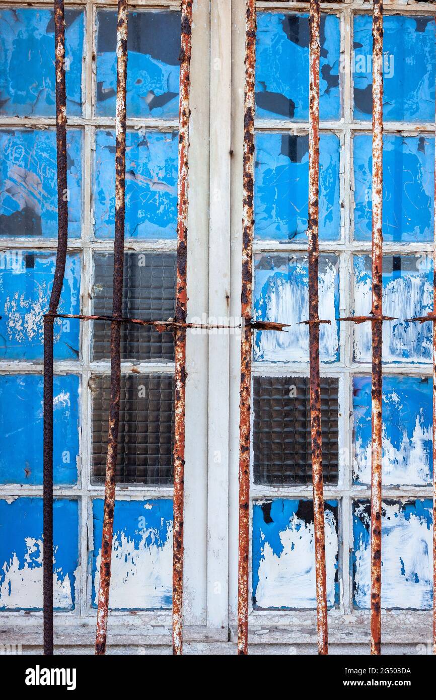 Decrepit window with painted glasses and rust-worn grille. Bonifacio ...