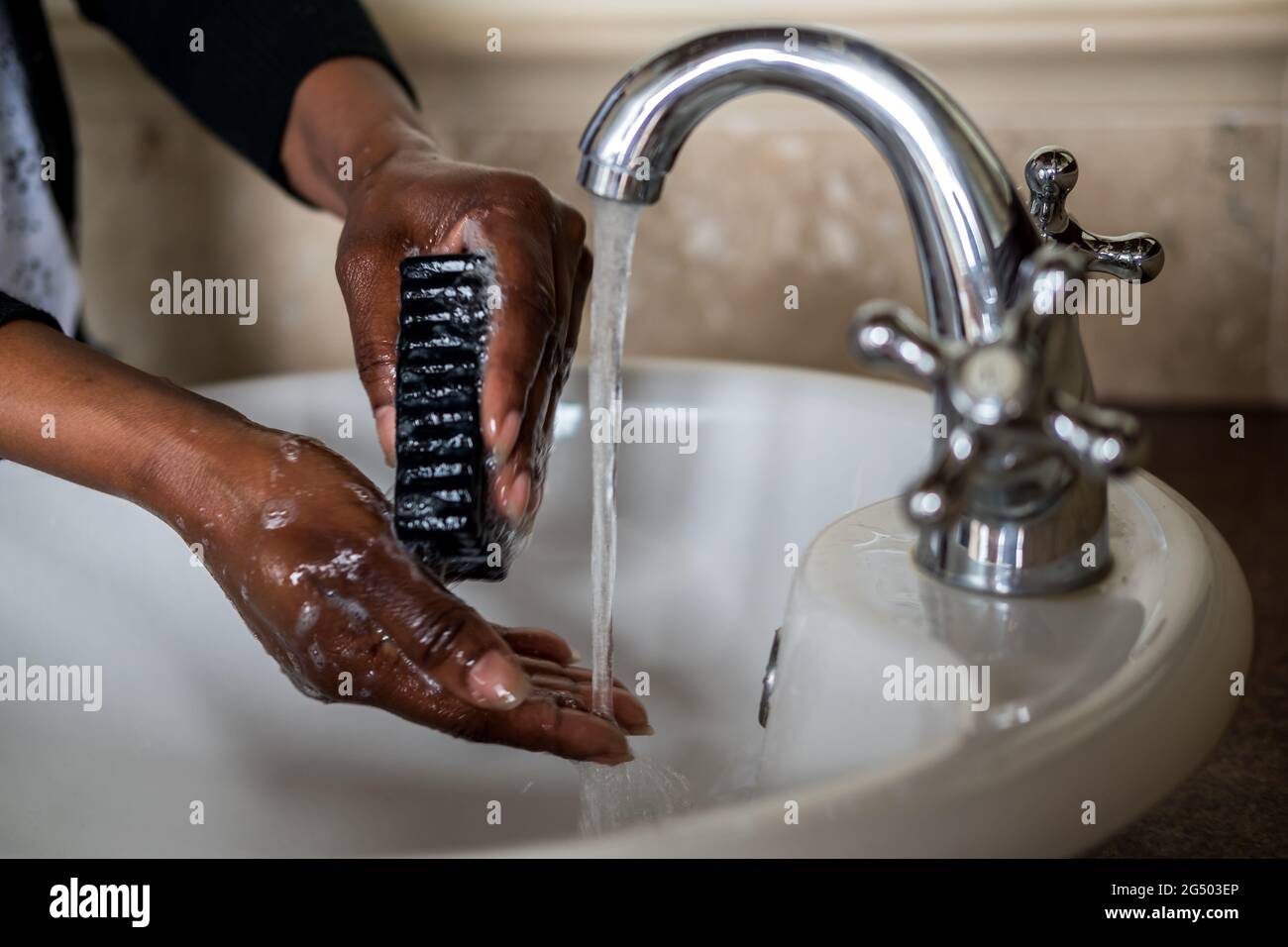 A black African American woman is washing her hands with organic soap ...