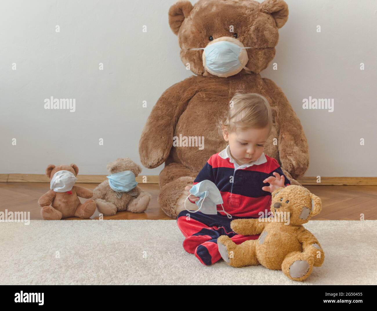 Child playing with his sick teddy bears wearing medical mask against ...