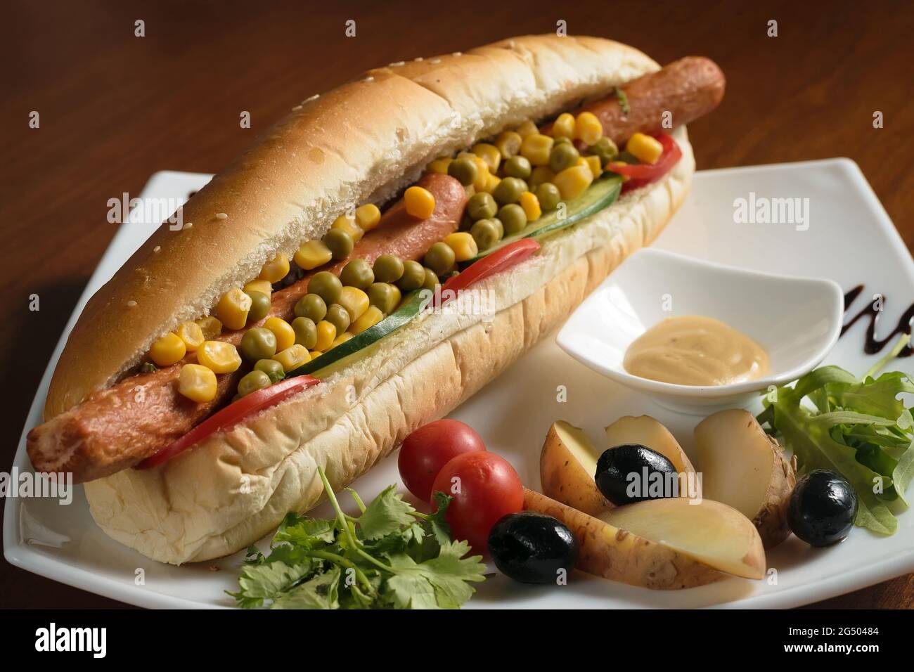 Long hot dog with two sausages close-up, with green peas and corn, with ...