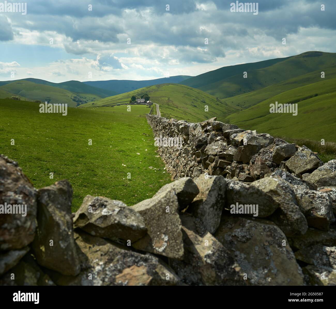 Remote Farm on hillside with stone wall and dramatic summer sky in the ...