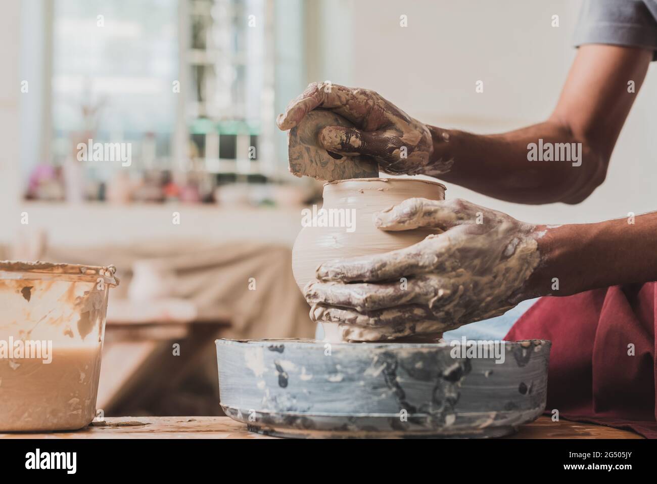 partial view of young african american man in apron sculpting pot on ...