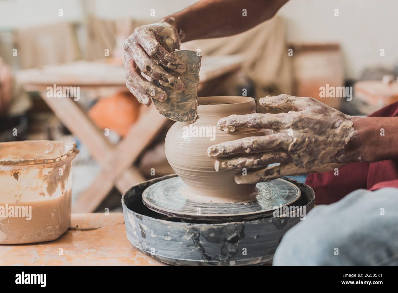 close up view of young african american man in apron sculpting pot on ...
