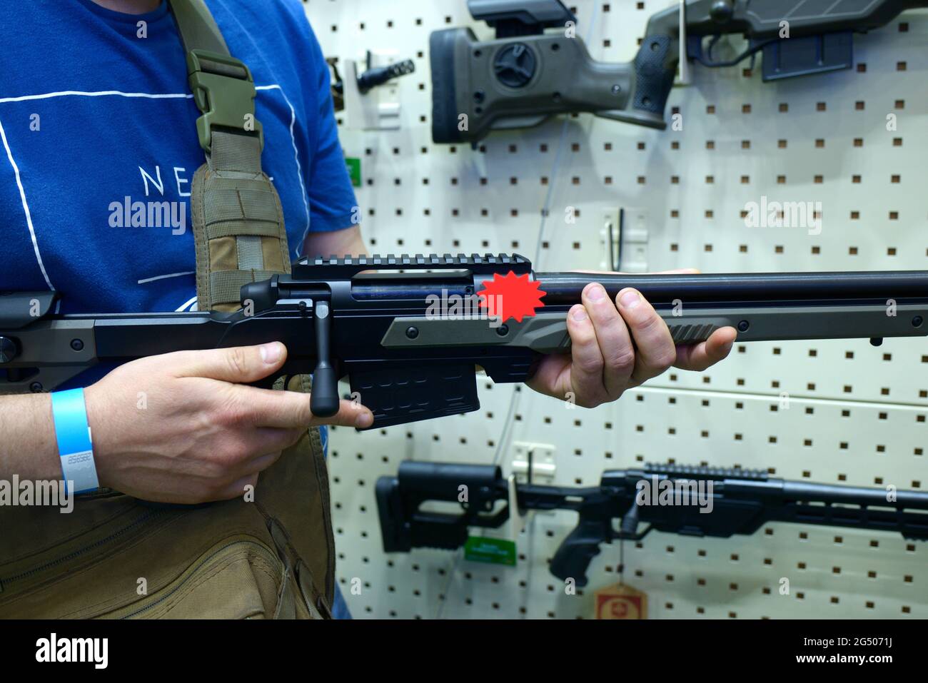 Male hands jerk the bolt of a a new model of a rifle in a gun shop ...