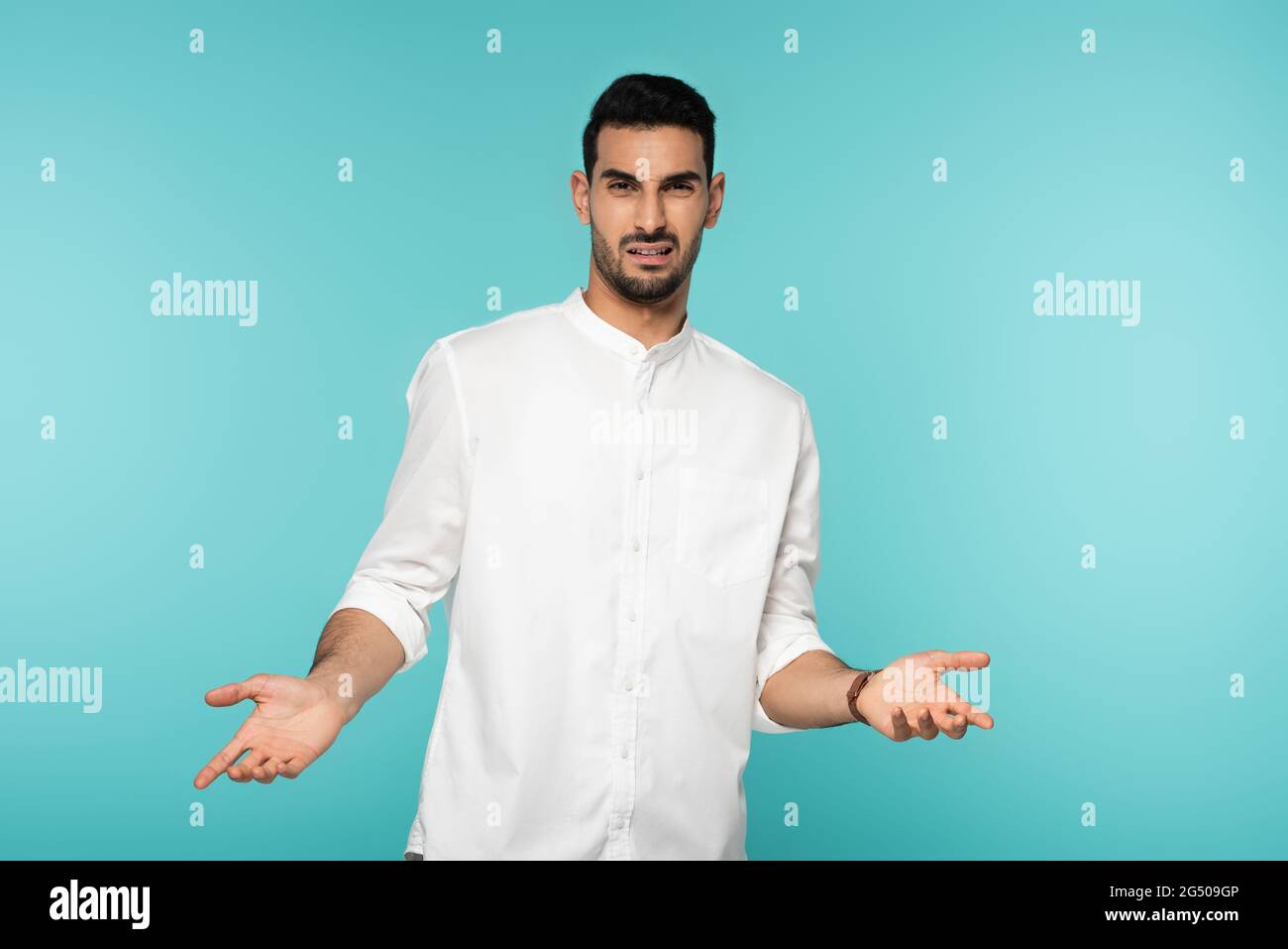 Confused arabian man pointing with hands isolated on blue Stock Photo ...