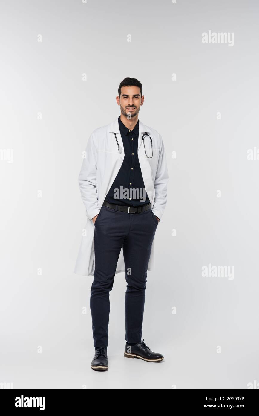Arabian doctor smiling at camera while standing on grey background ...