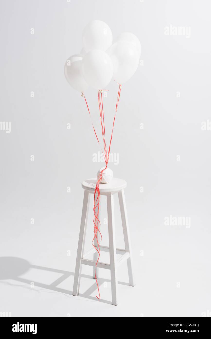 lightweight balloons above stool with ball of thread on white Stock ...