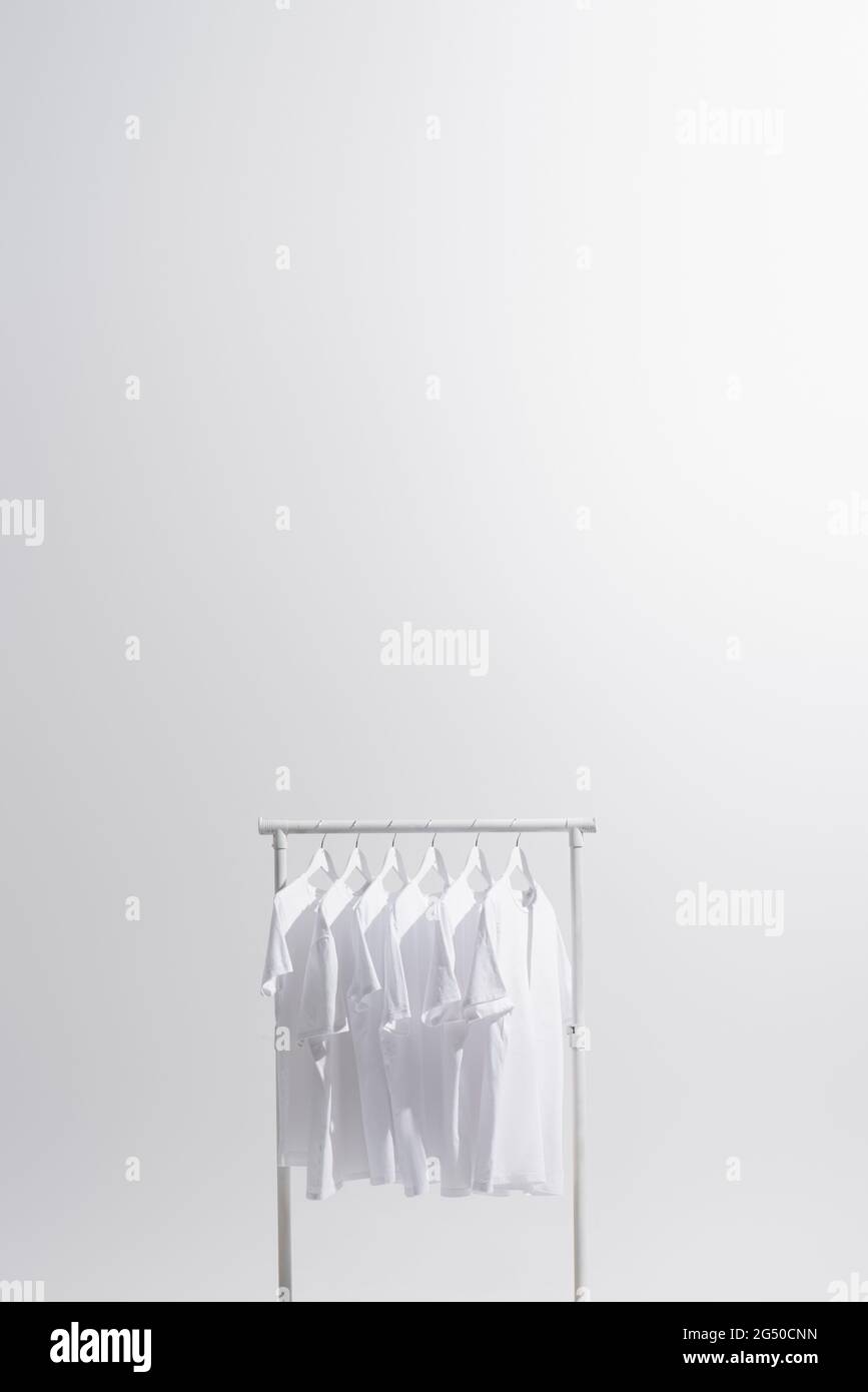white t-shirts hanging on clothes rack isolated on grey Stock Photo - Alamy