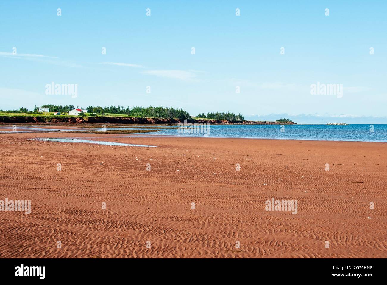 Scenic view of red sand of Prince Edward Island with water, cottages ...