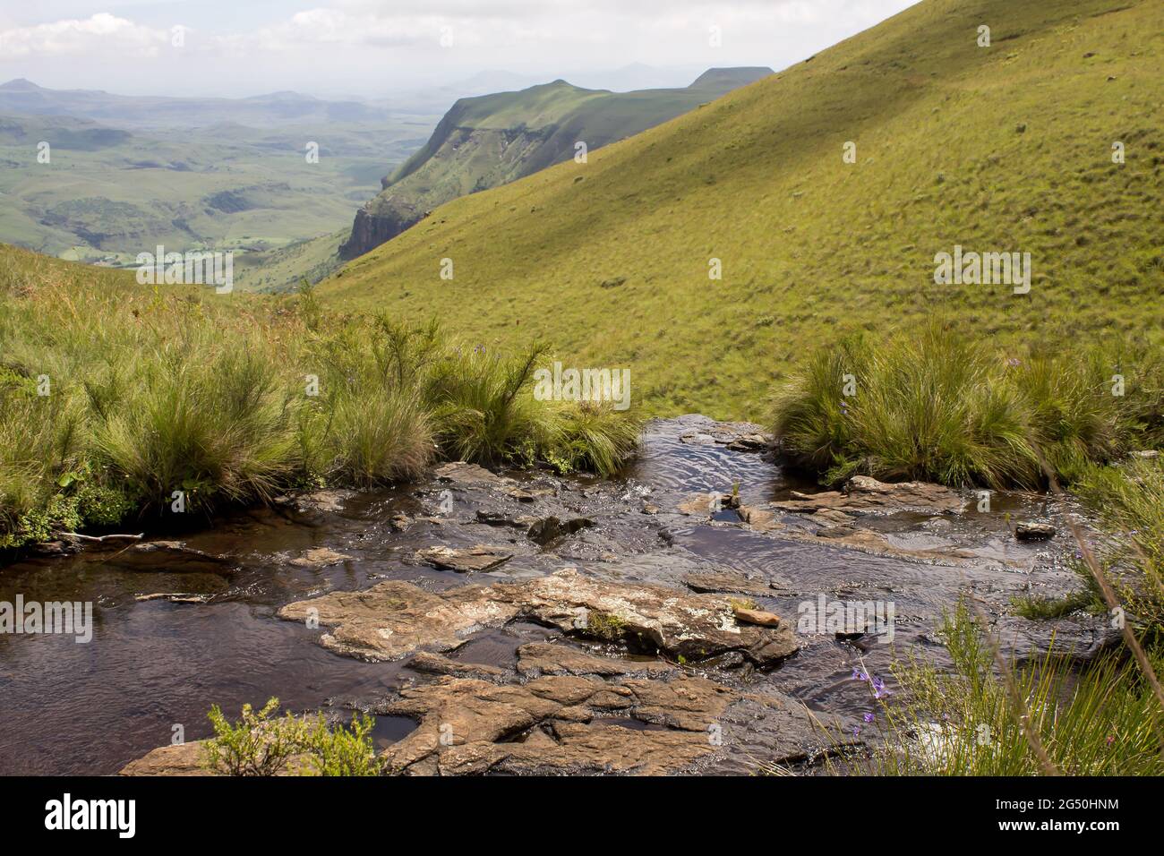 A small mountain stream flowing down a cliff in the grass covered ...