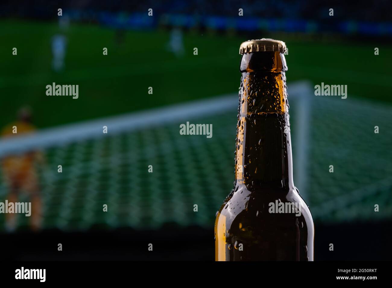 A bottle of beer on the background of a broadcast of a football match ...