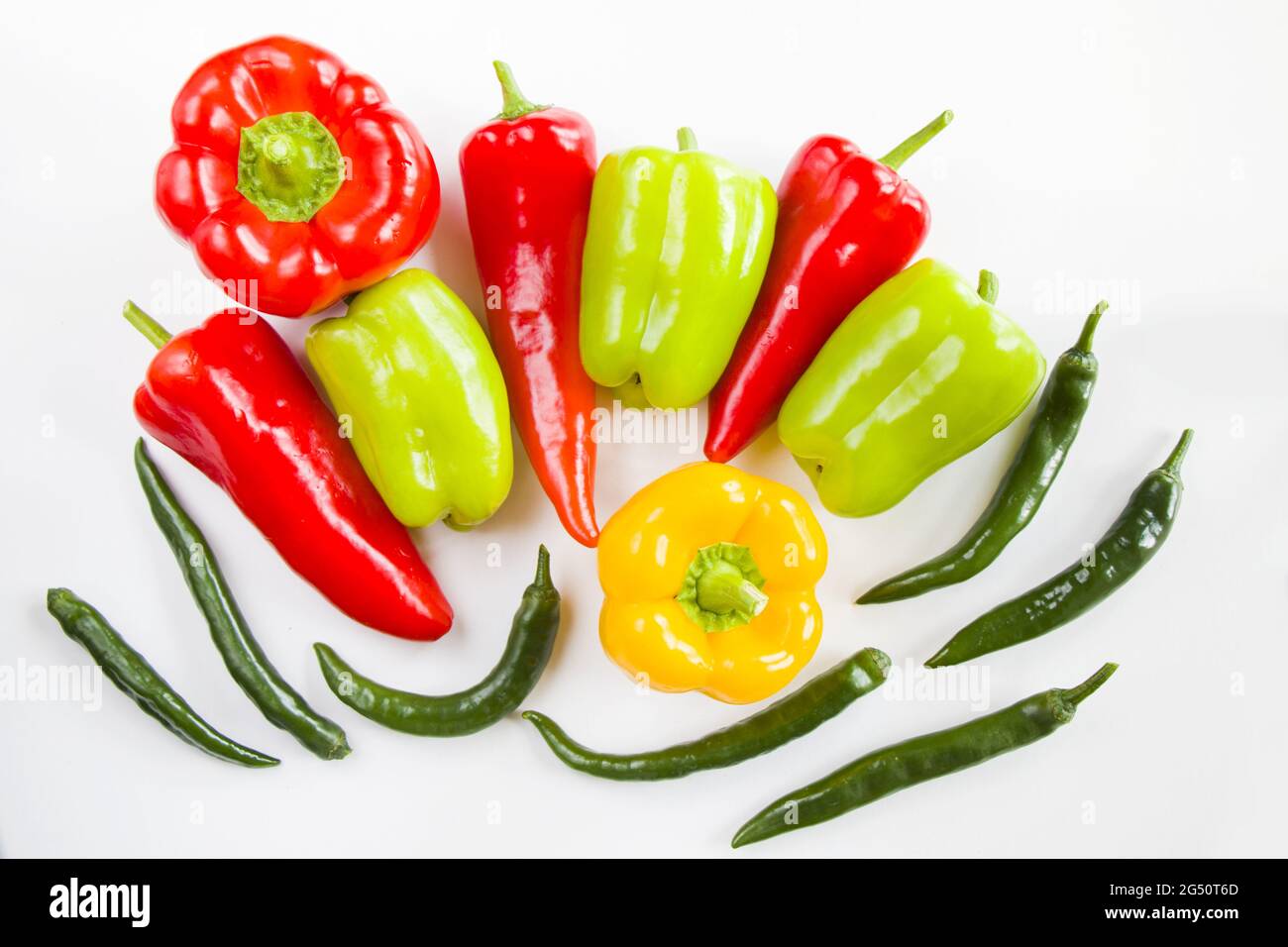 Top view of colorful bell peppers and green spicy peppers on a white ...