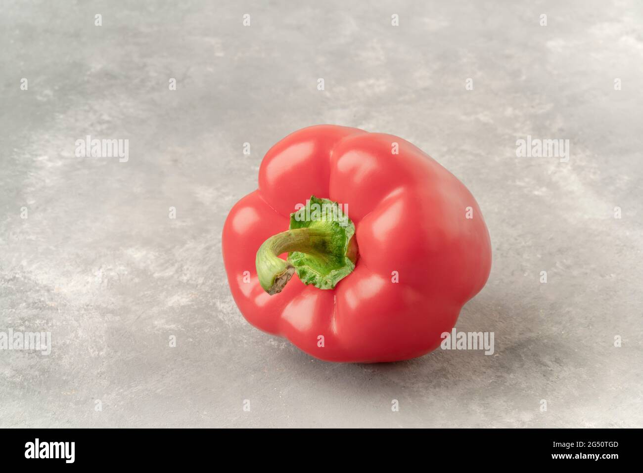 closeup of one ripe red bell pepper on gray background with copy space ...