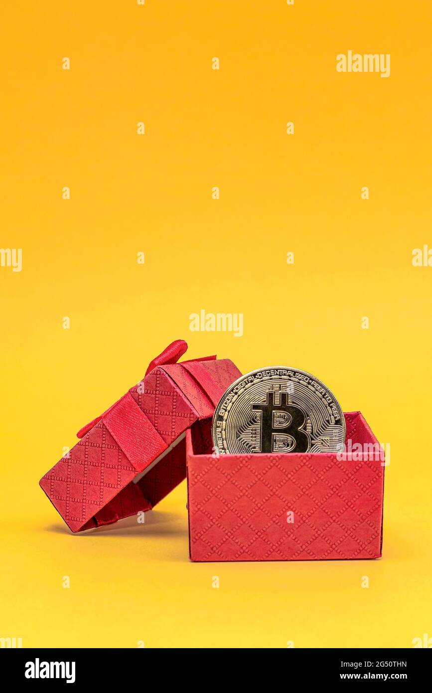 BTC gift. Bitcoin coin in a gift box on a yellow background. Postcard ...