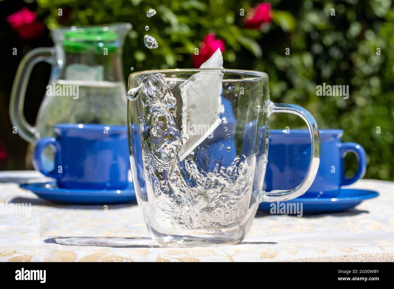 A tea bag falls into a mug with splashing water Stock Photo - Alamy
