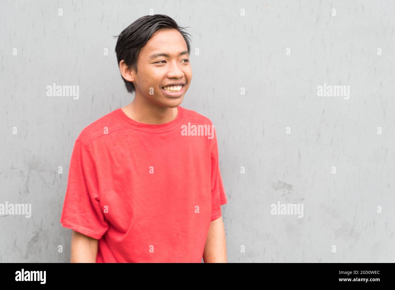 Happy smiling Indonesian guy wearing a red t-shirt posing on a white ...