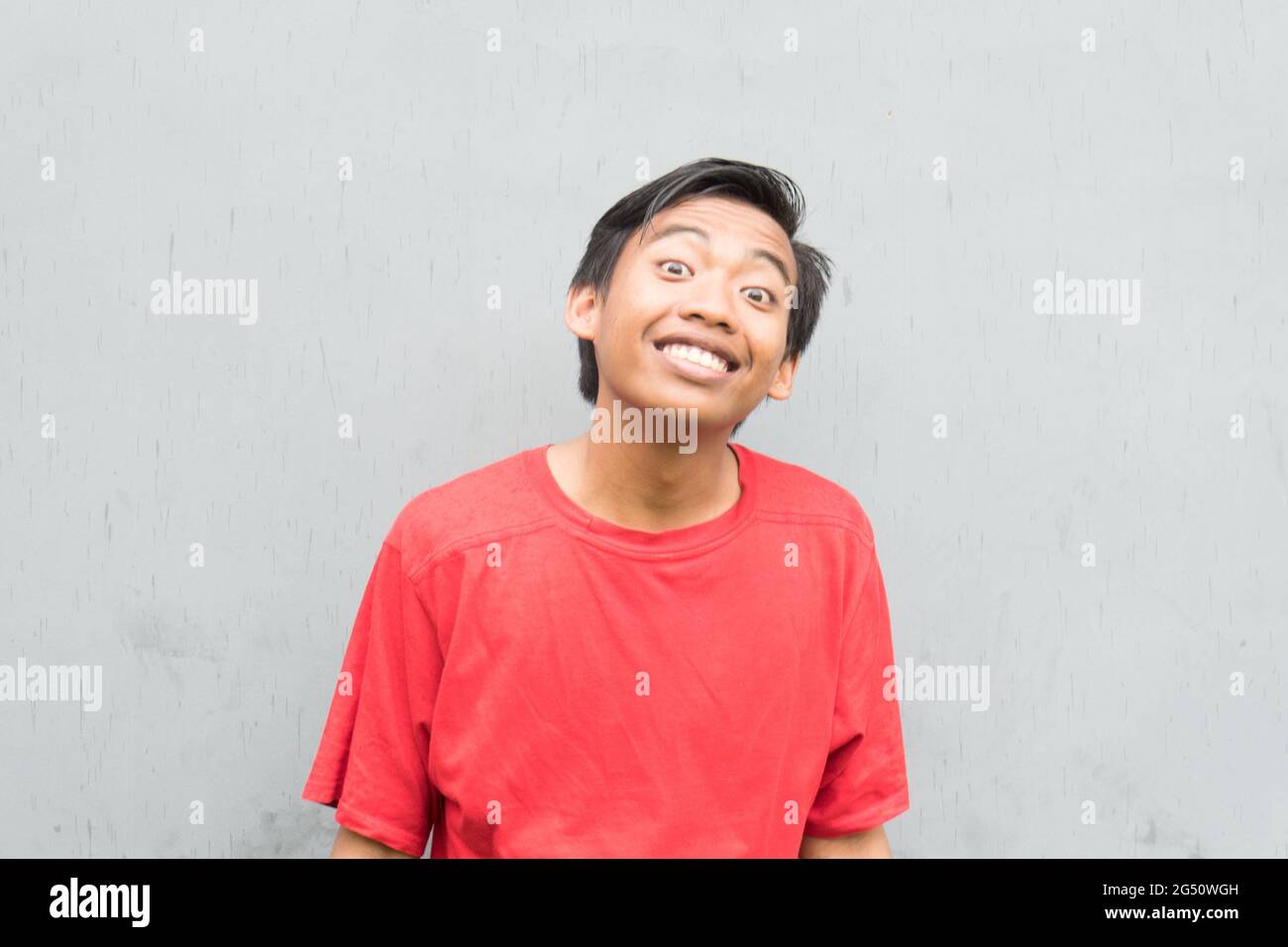 Happy smiling Indonesian guy wearing a red t-shirt posing on a white ...