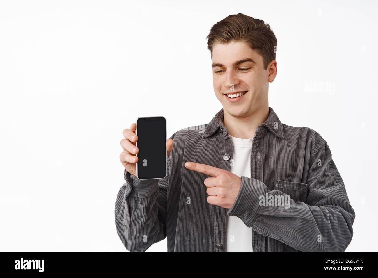 Close up of cheerful caucasian guy pointing finger at smartphone ...