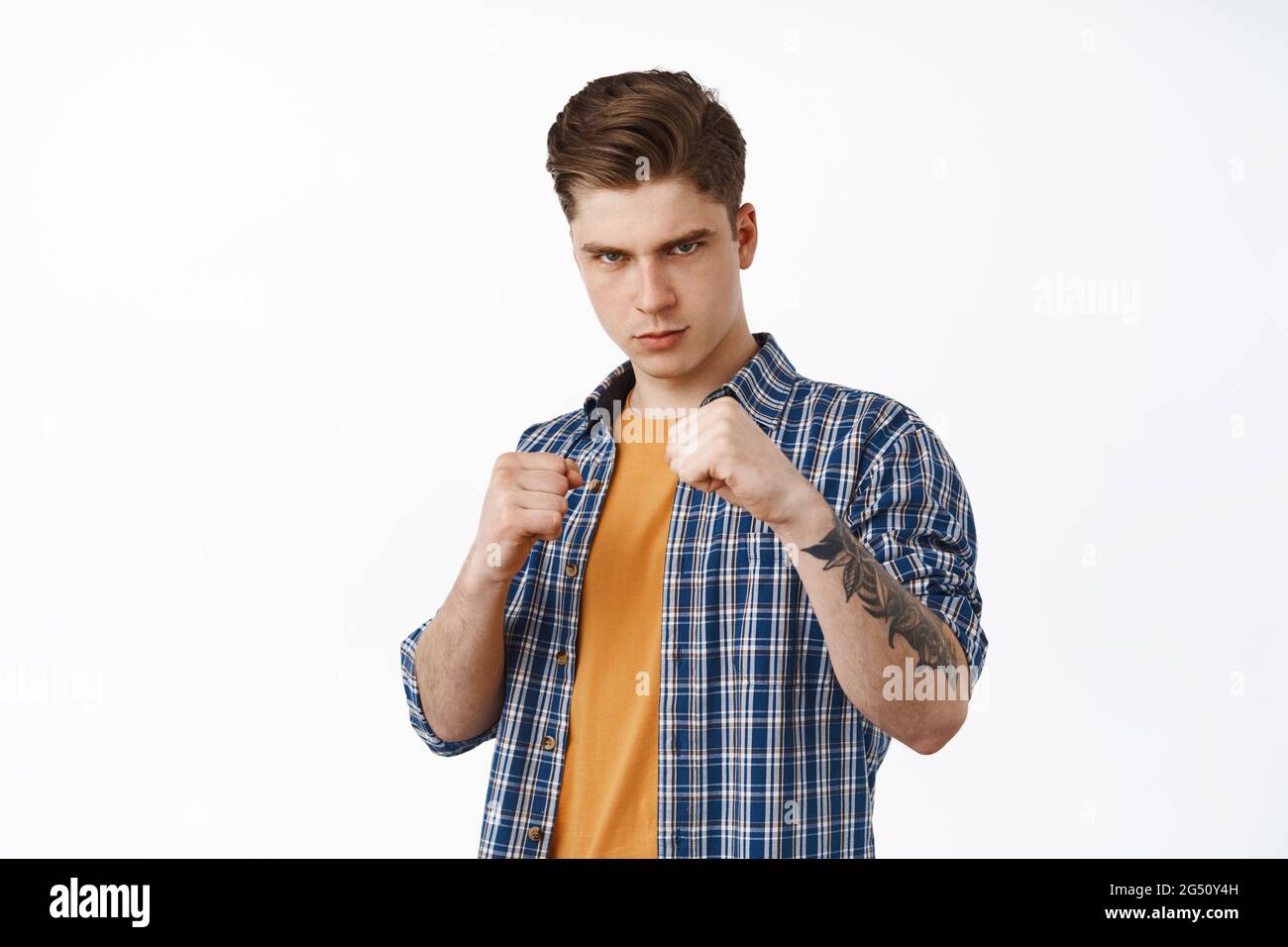 Serious young guy fighter raise fists, standing in boxing confident ...