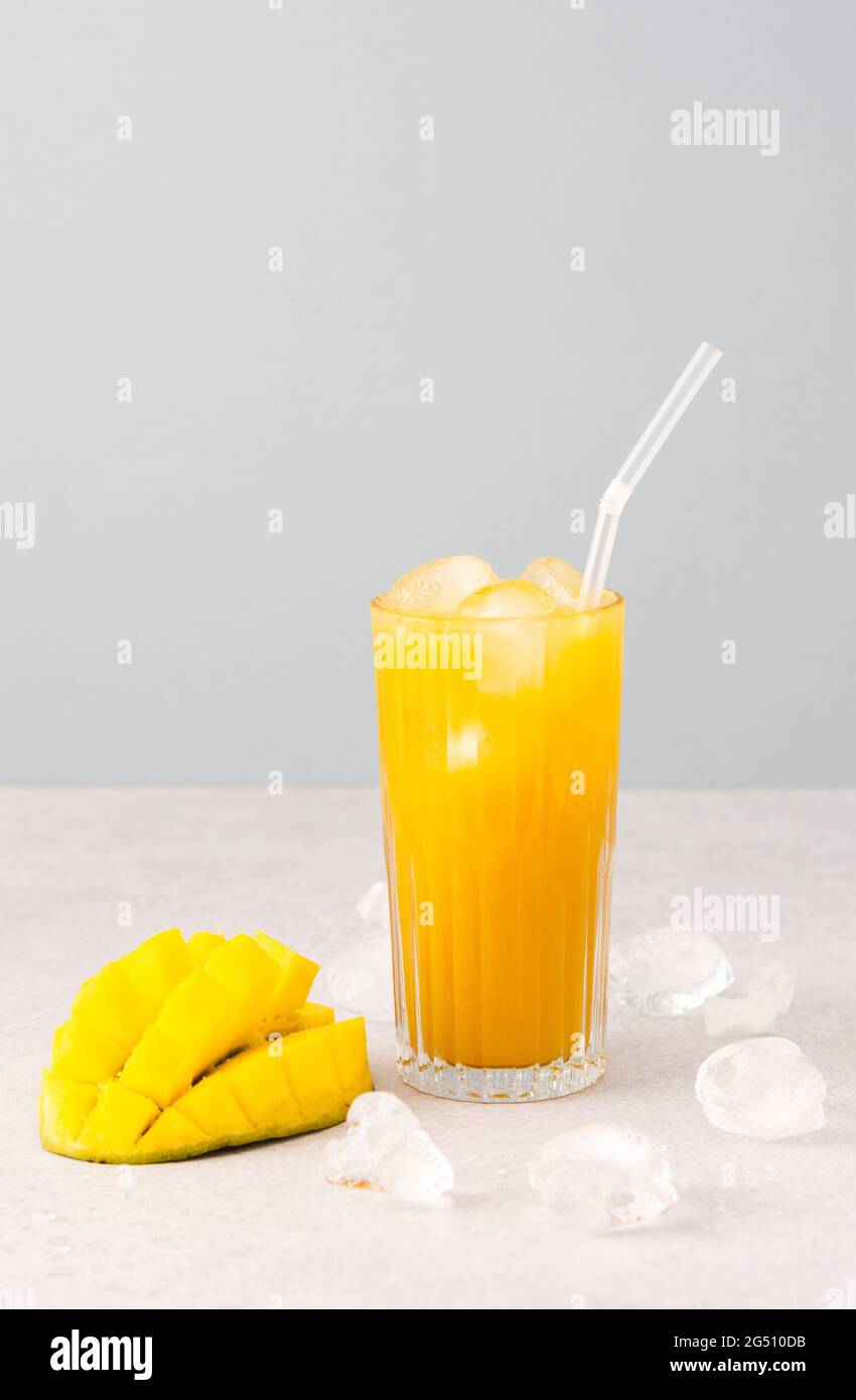 Freshly squeezed mango juice with ice in glass with a straw, ripe cut ...