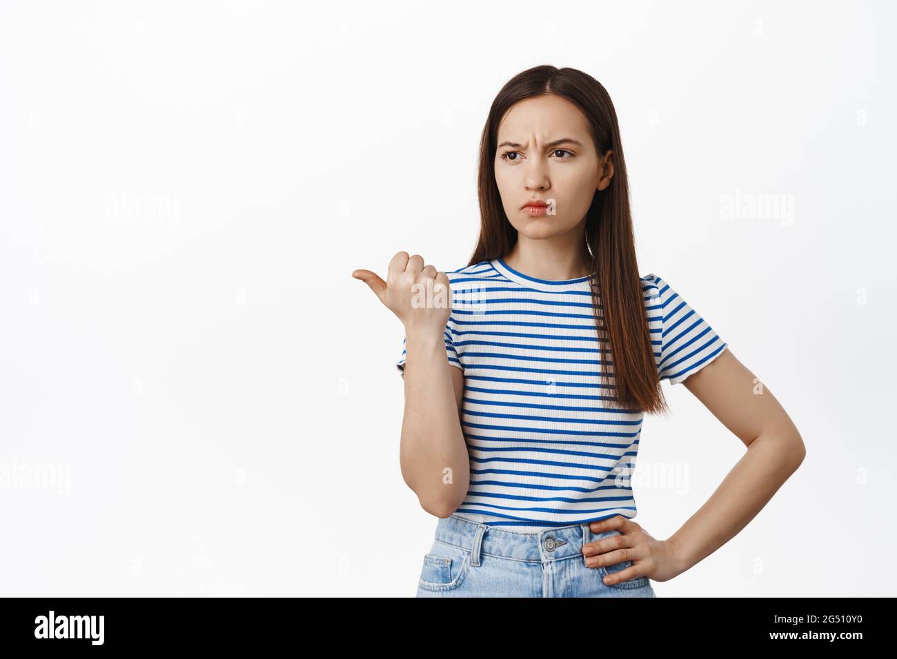 Skeptical and picky girl looking, pointing left with furrow eyebrows ...