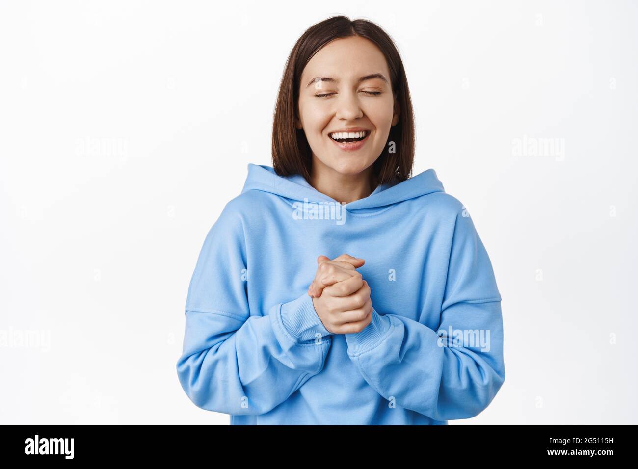 Image of hopeful smiling girl close eyes, hold hands clenched and ...