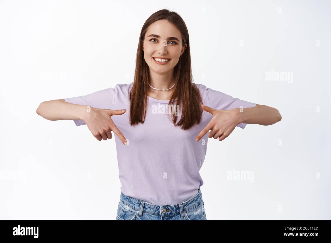 Portrait of cute happy woman pointing down, smiling white teeth and ...