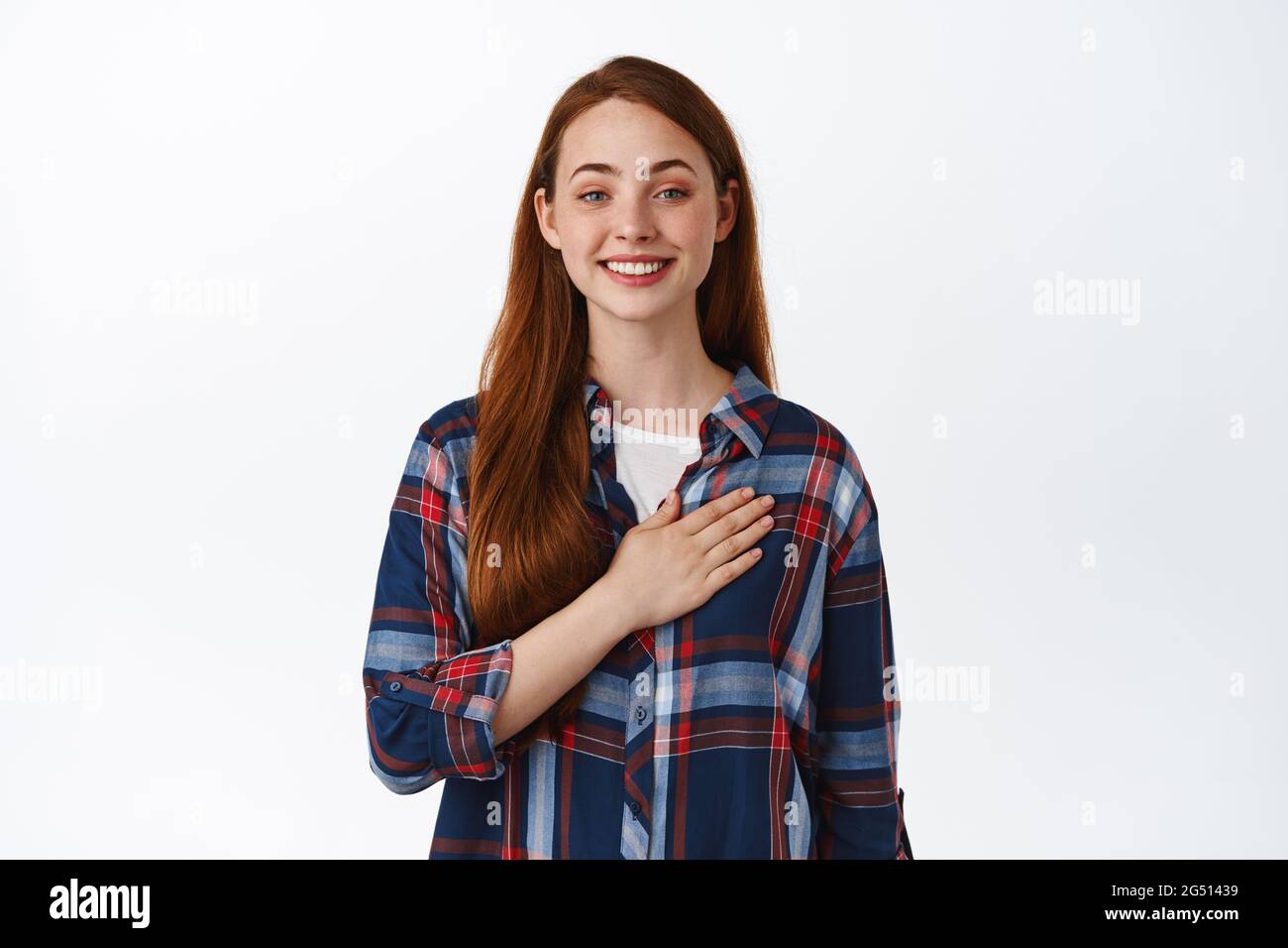 Smiling cute teen girl, hold hand on heart, look happy, feel grateful ...