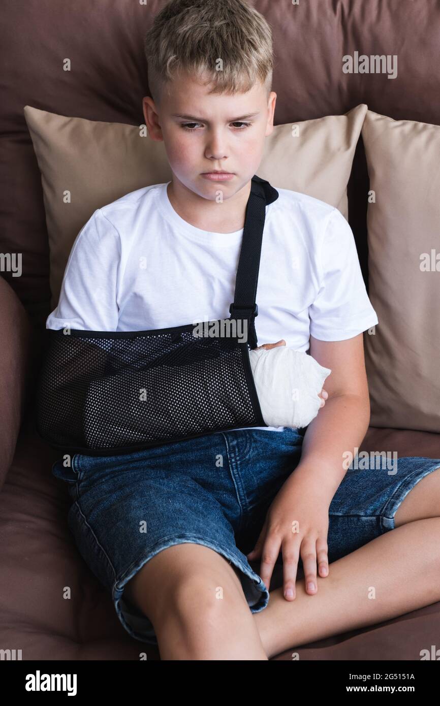 Sad boy with a broken arm and wounds on his leg. Gypsum on a child's ...