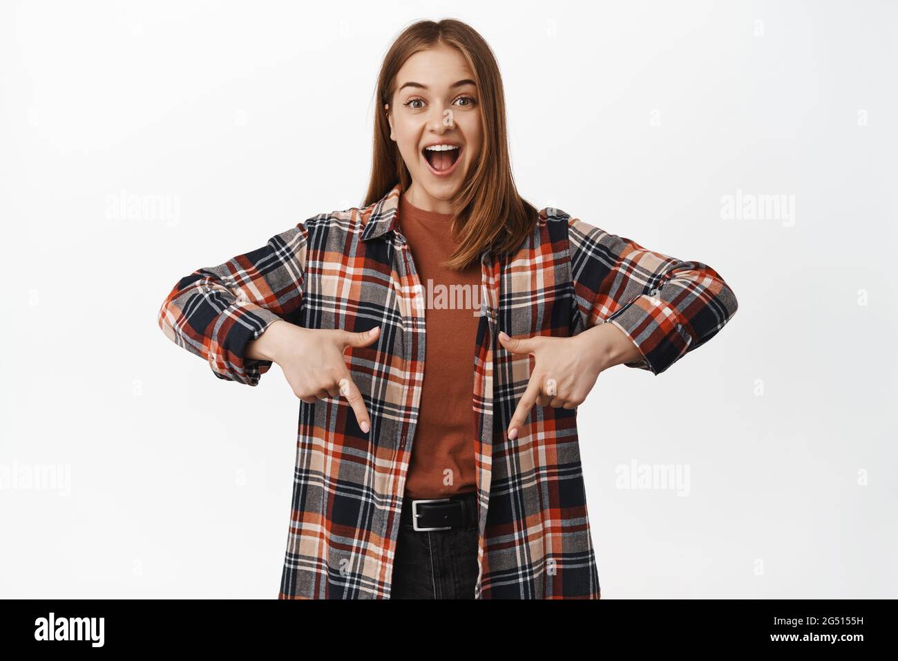 Portrait of happy young woman smiling, pointing down at awesome new ...